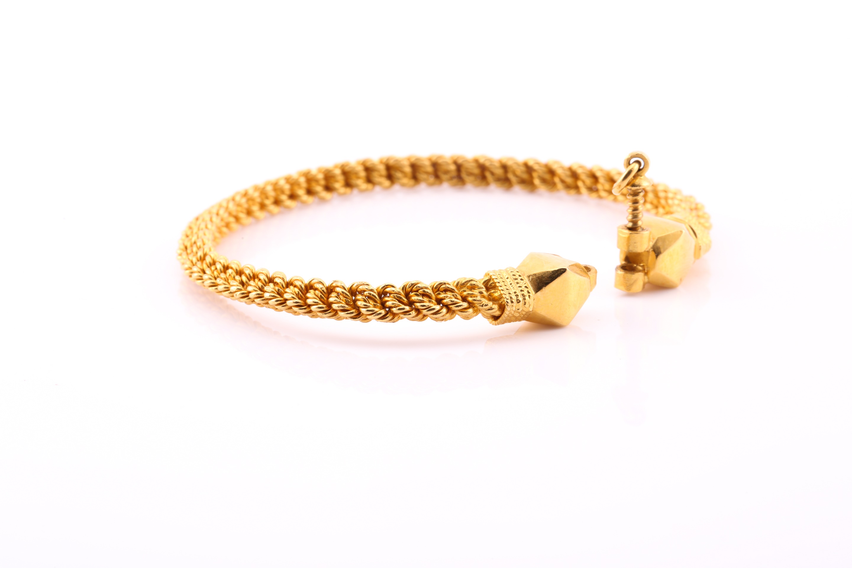 Lot 428 - A yellow metal torque style bangle, the rope